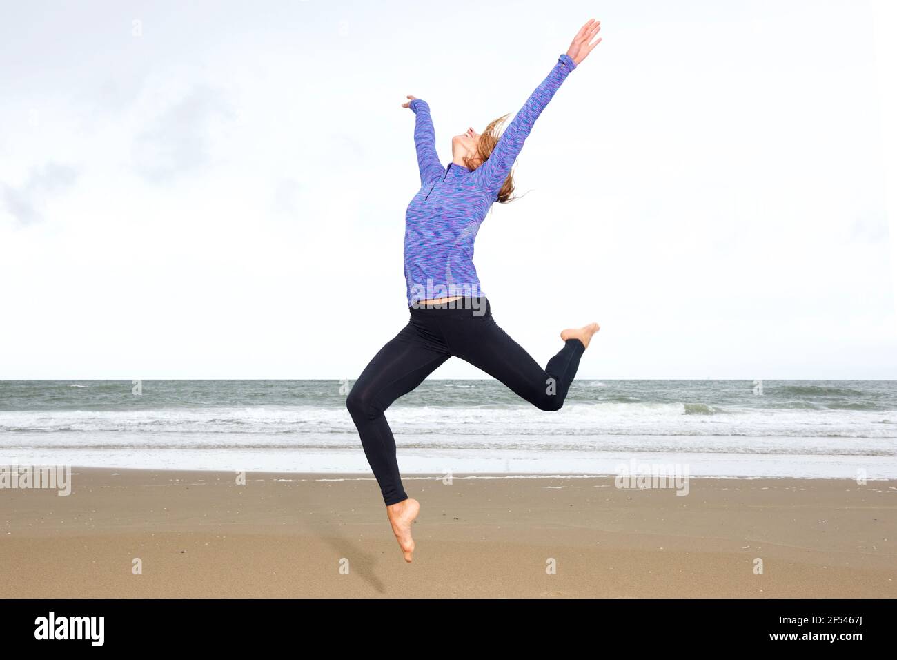 Portrait of athletic woman leaping in air with arms outstretched Stock ...