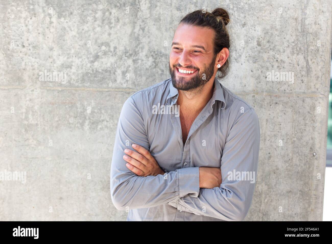 Portrait of smiling modern man with beard standing with arms crossed ...