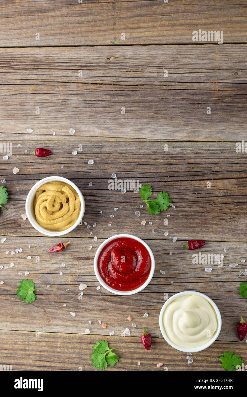 Set of various sauces with spices on natural wooden background ...