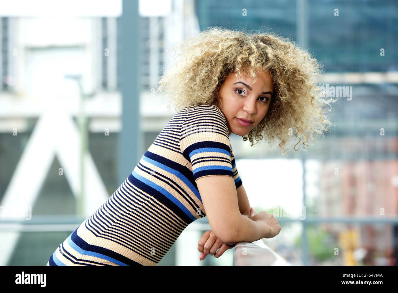 Portrait of serious young woman leaning on railing Stock Photo - Alamy
