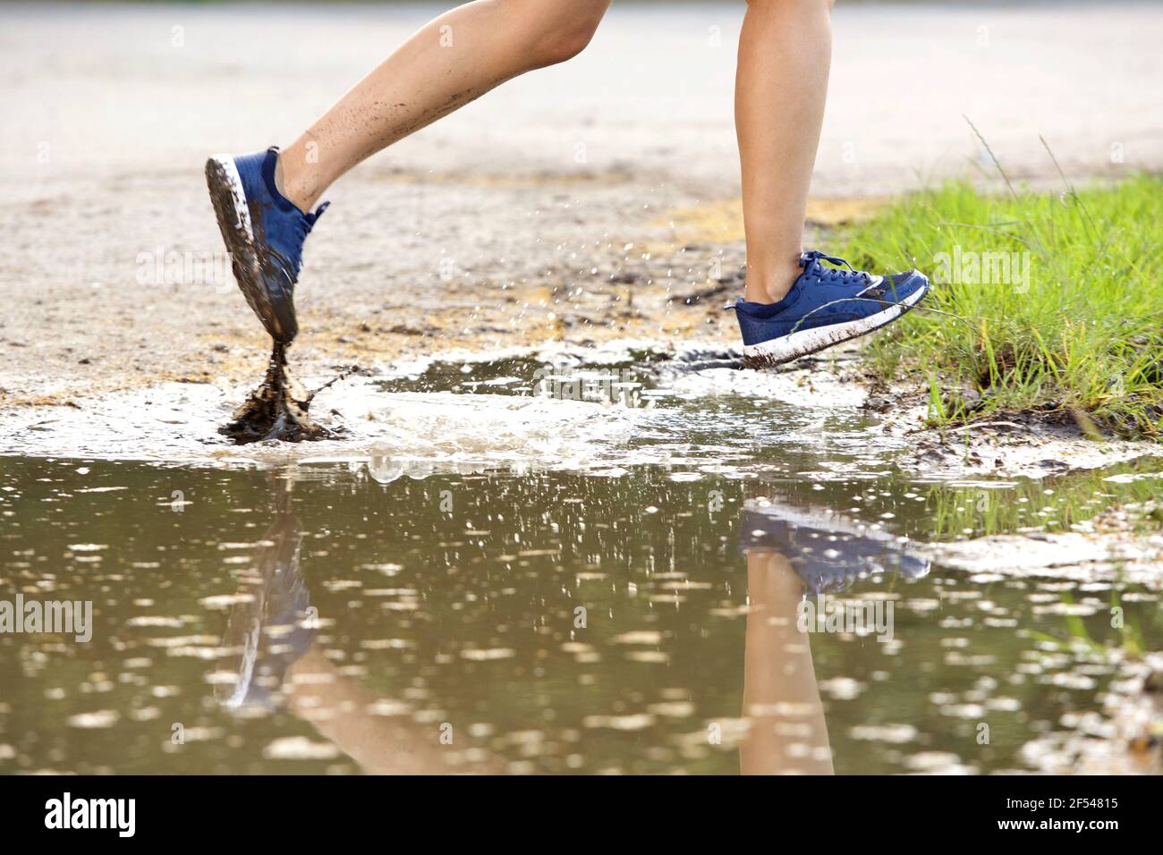 Side portrait female runner legs running in mud Stock Photo - Alamy