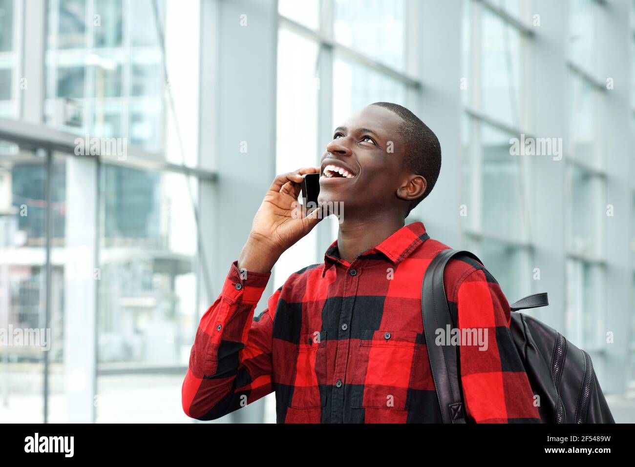 Portrait of cheerful young african student talking on cell phone at ...