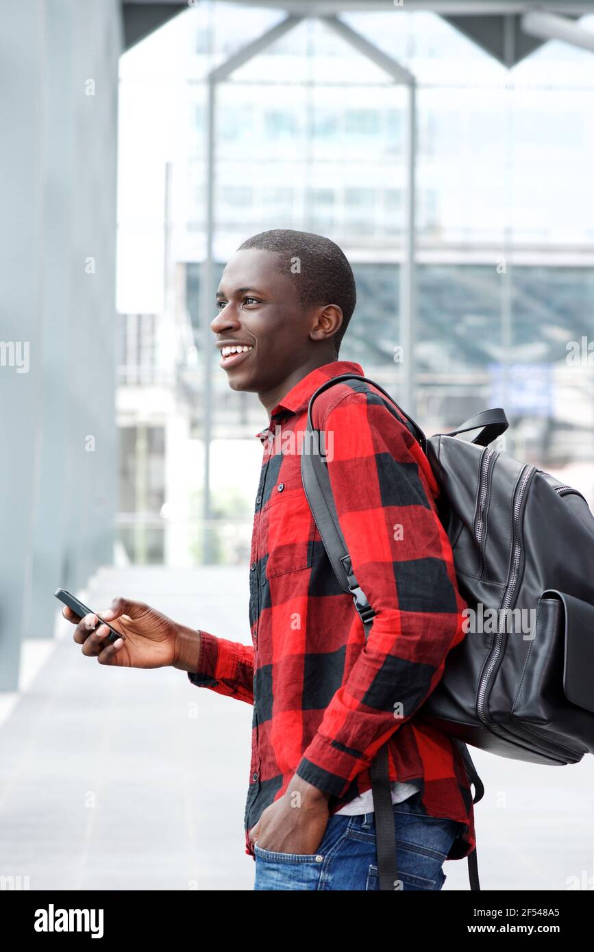 Side portrait of young african student with mobile phone at railway ...