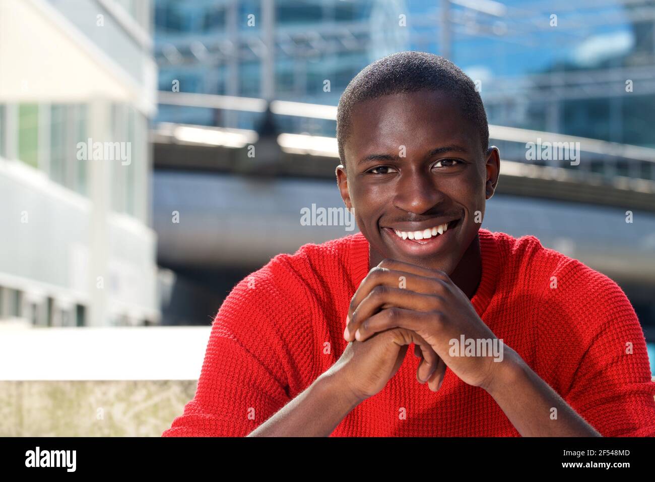 Portrait of handsome young black guy sitting outdoors and smiling Stock ...