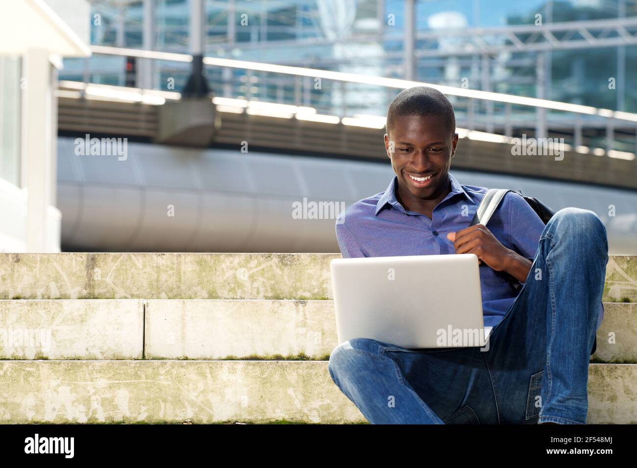 Portrait of young student sitting outdoors and using laptop Stock Photo ...