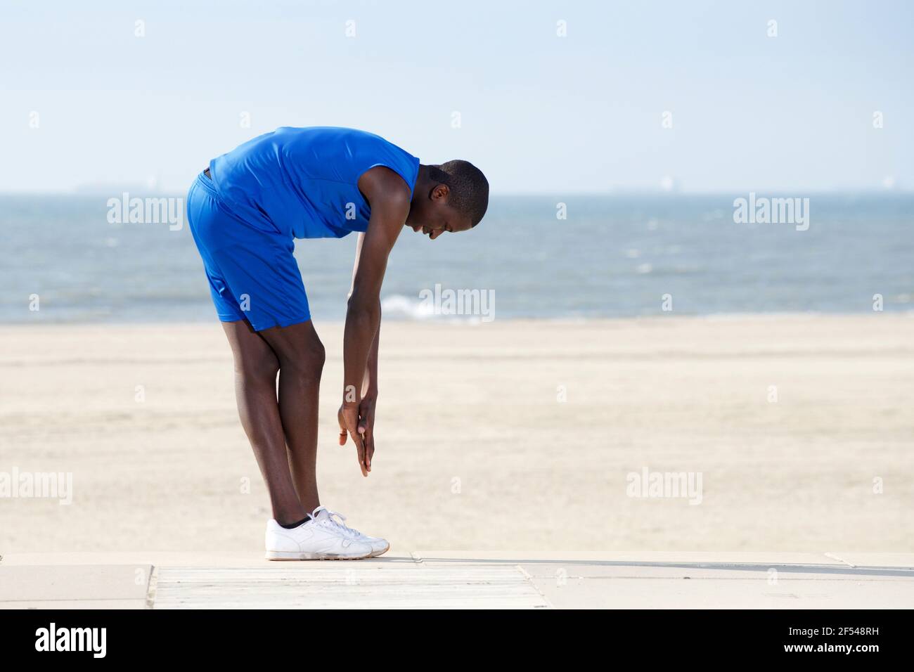Full body side portrait of fit young guy exercising on the beach Stock ...