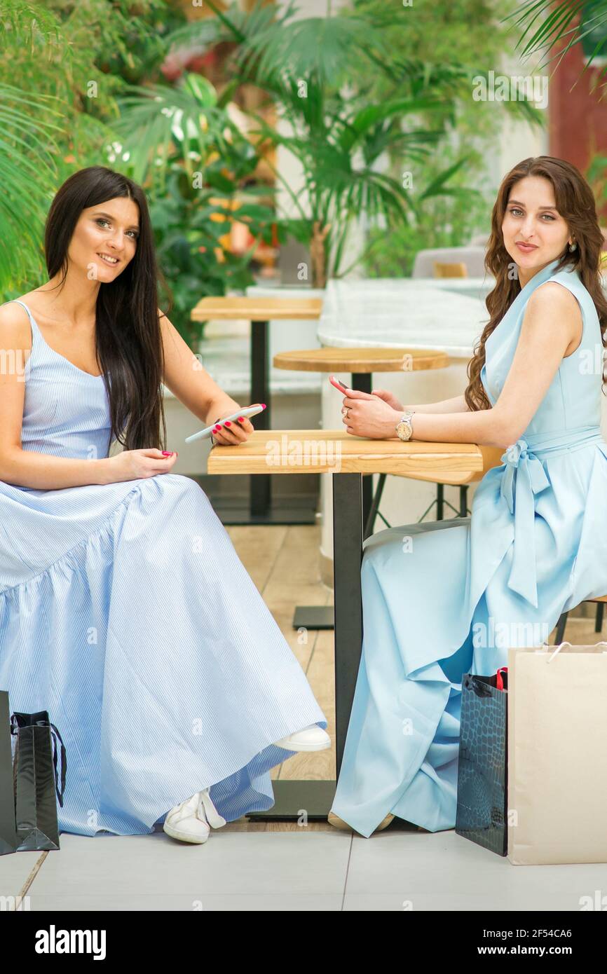 Two beautiful young women sitting at the table with smartphones and ...