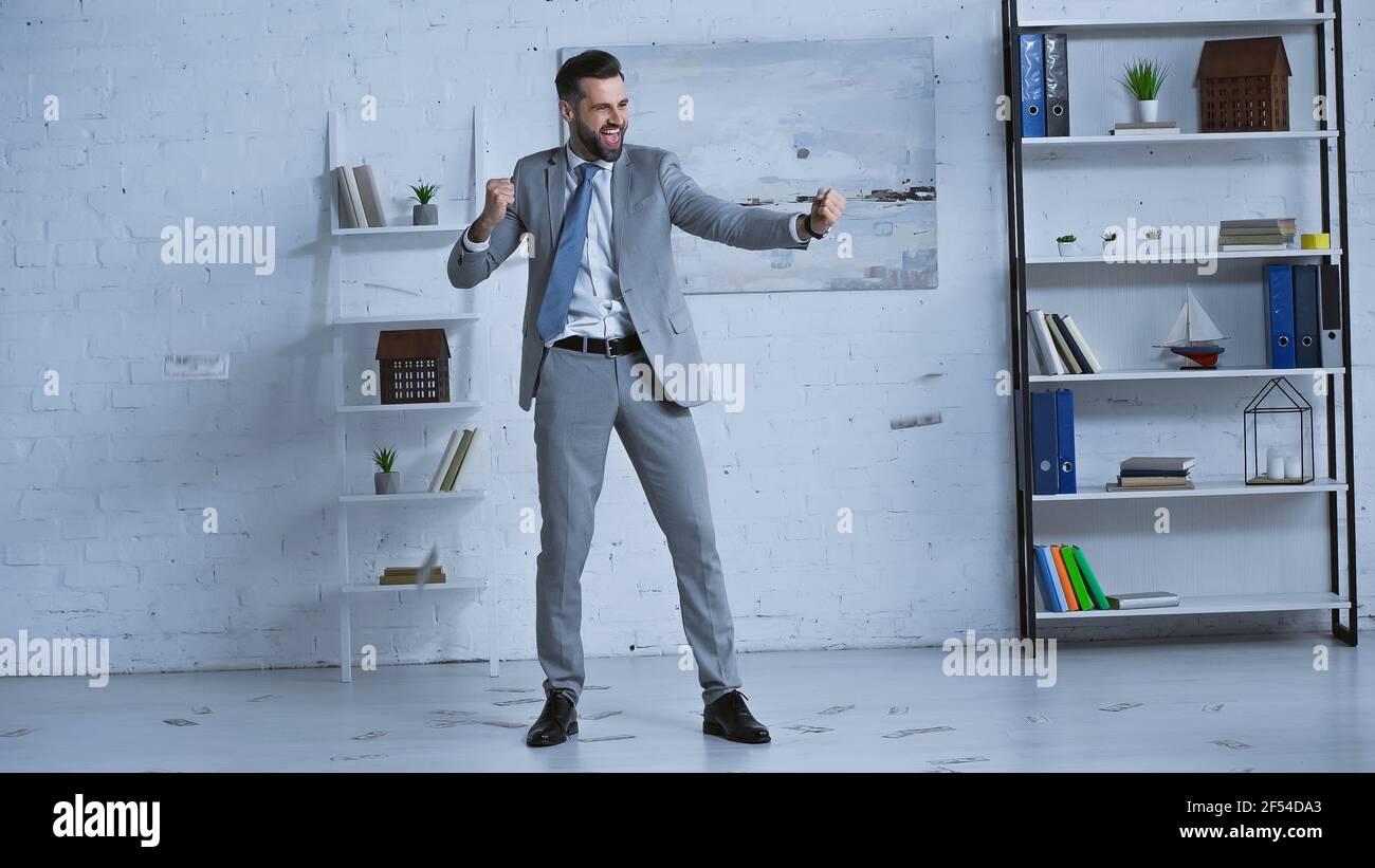 full length view of excited businessman showing triumph gesture in ...
