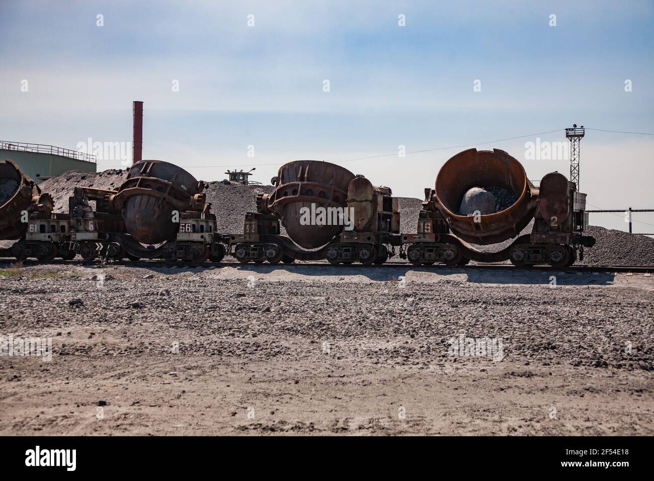 Metallurgical plant. Slag cars train on track. Blue sky background ...