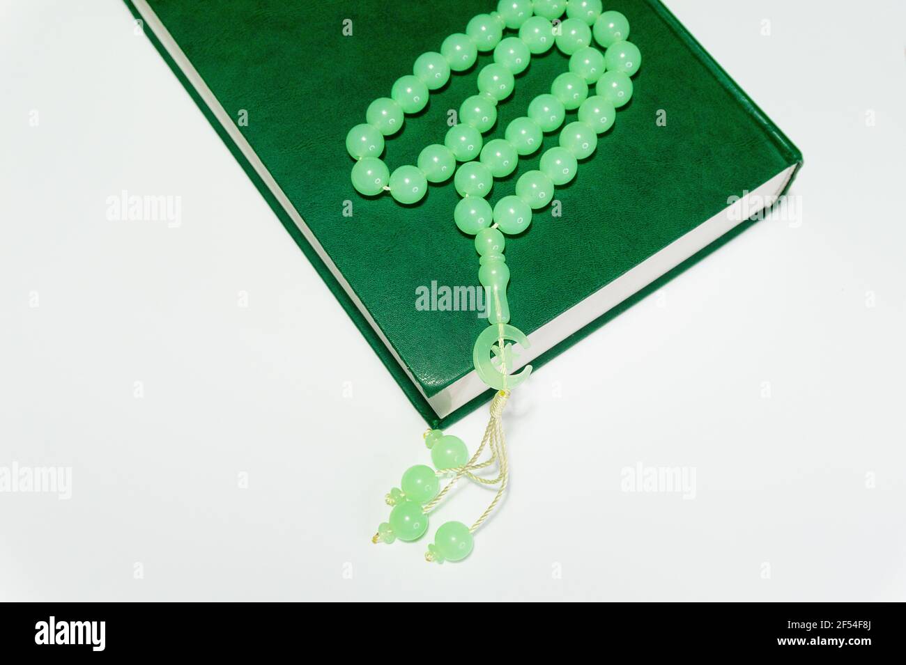 Islamic rosary beads of green color lie on the holy book of Muslims on ...