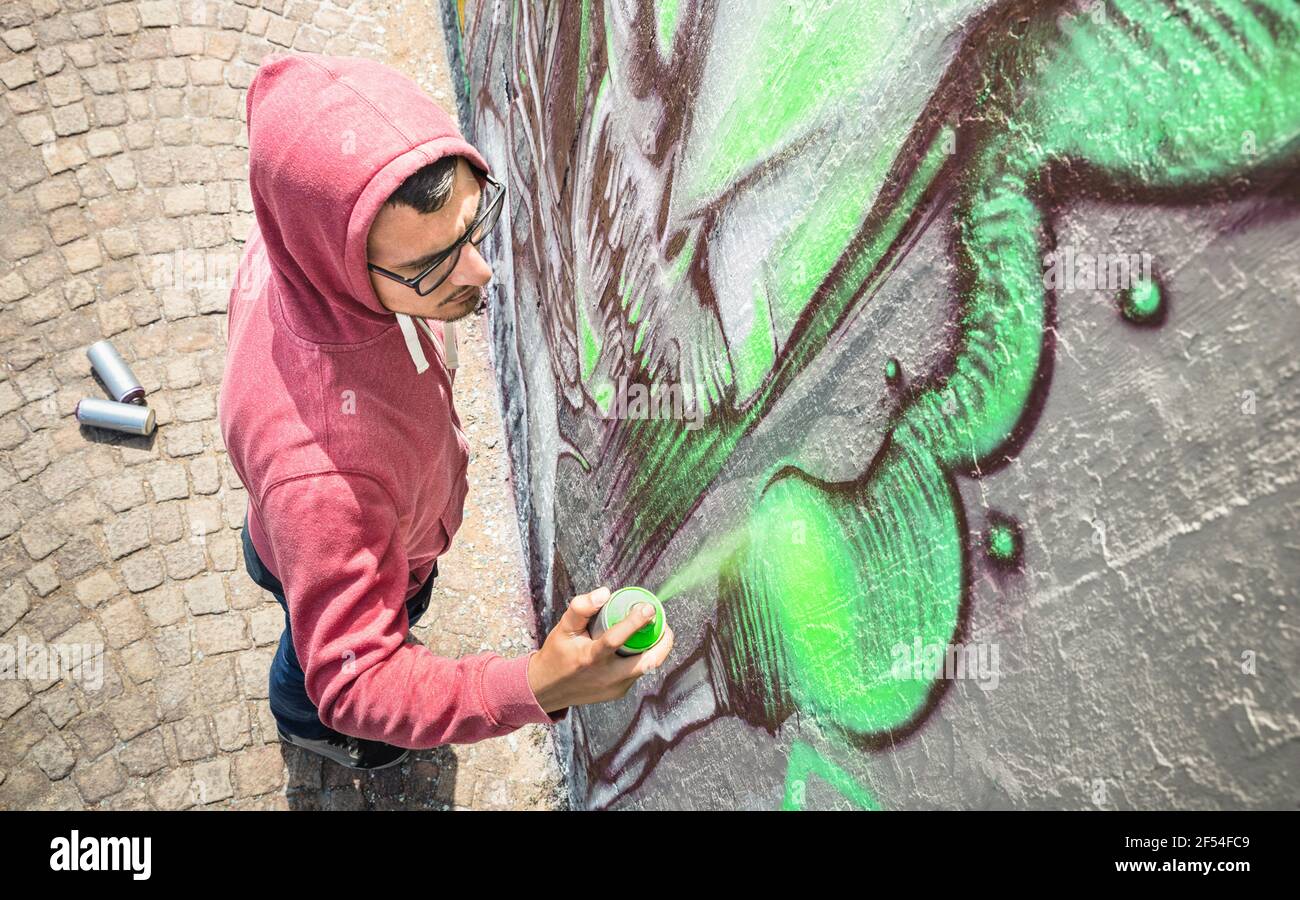 Street artist painting colorful graffiti on generic wall - Modern art ...