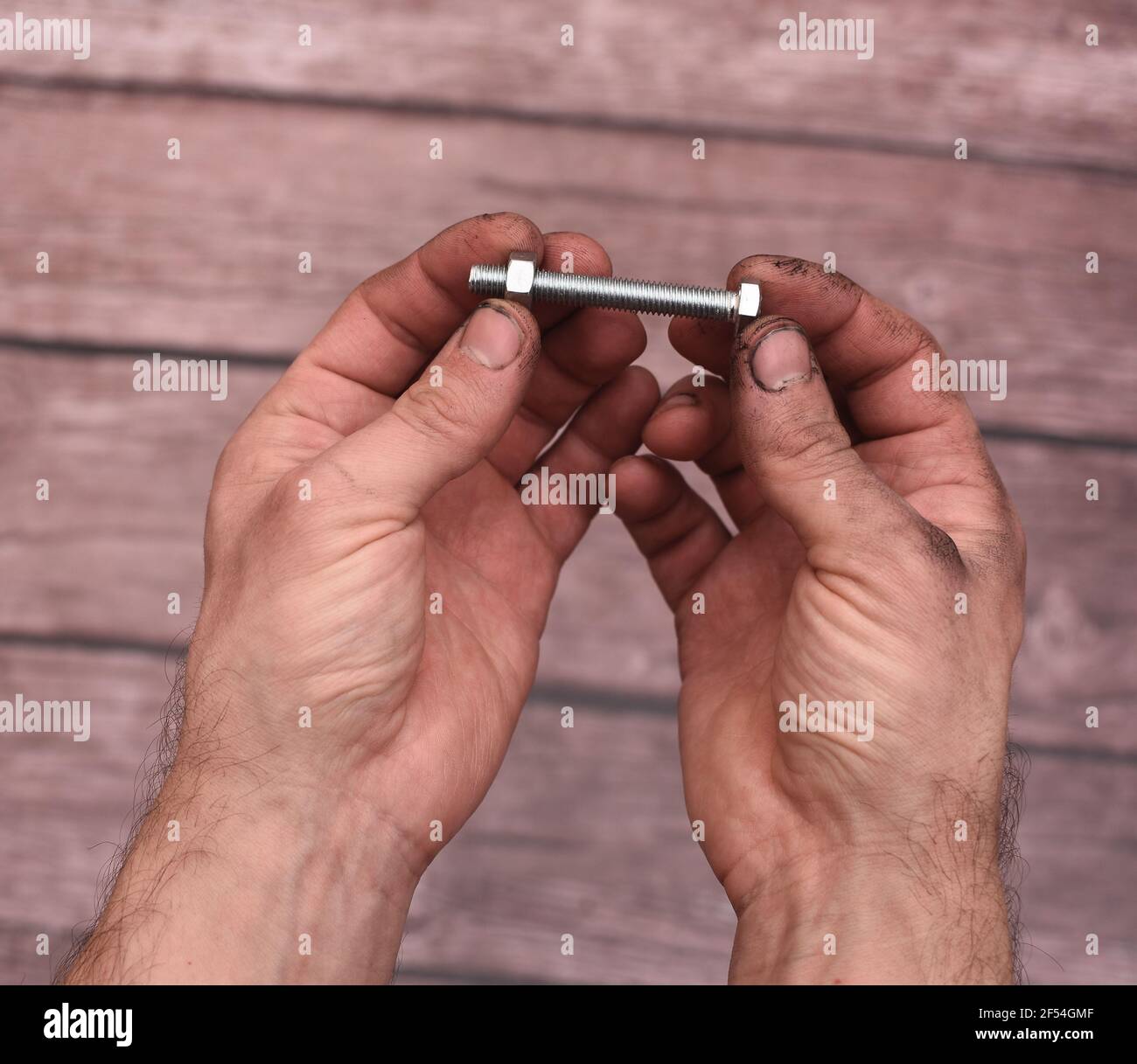 The man is holding a bolt with a screwed nut Stock Photo - Alamy