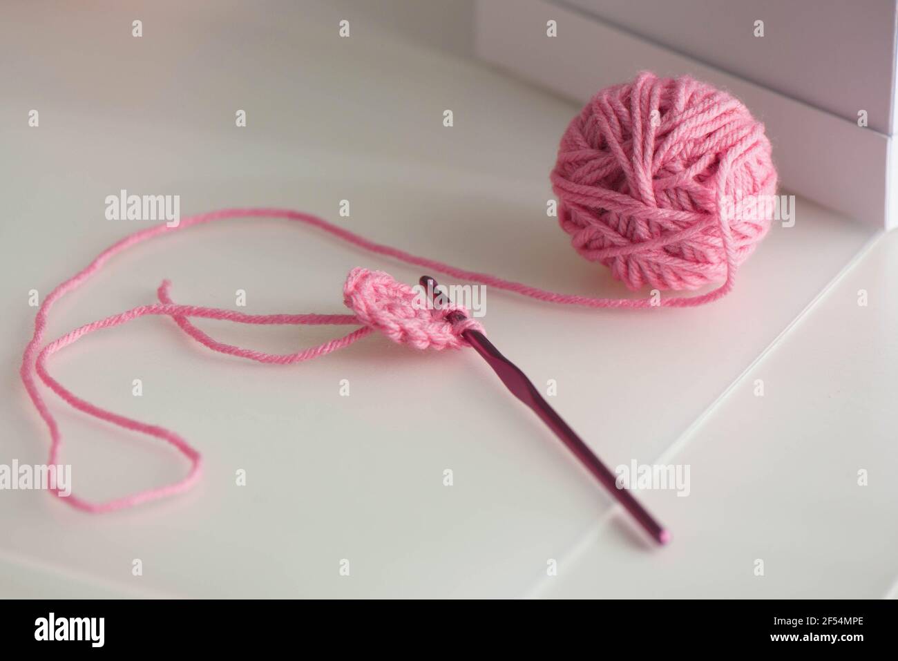 Pink yarn ball with woolen thread on white background Stock Photo - Alamy