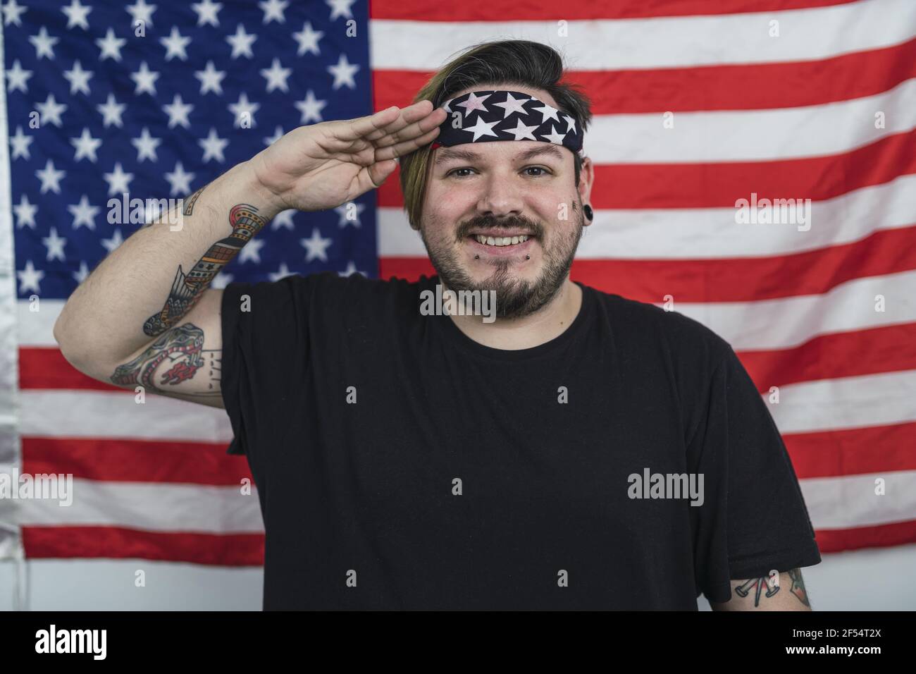 Bearded caucasian man with a bandana smiling while giving a salute in ...