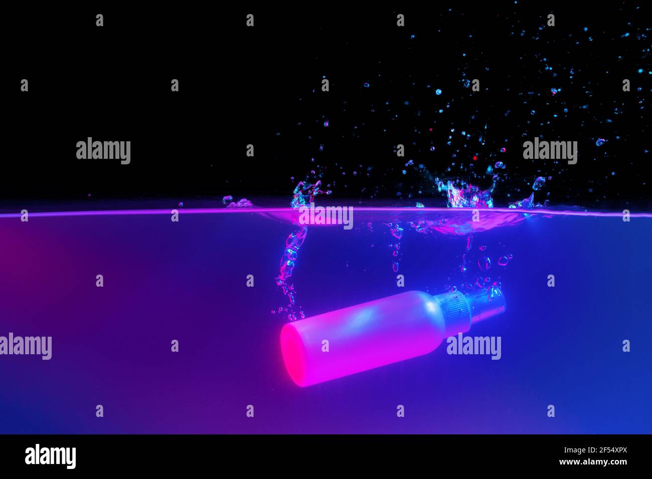 Skincare product bottle falling into water against black background in ...