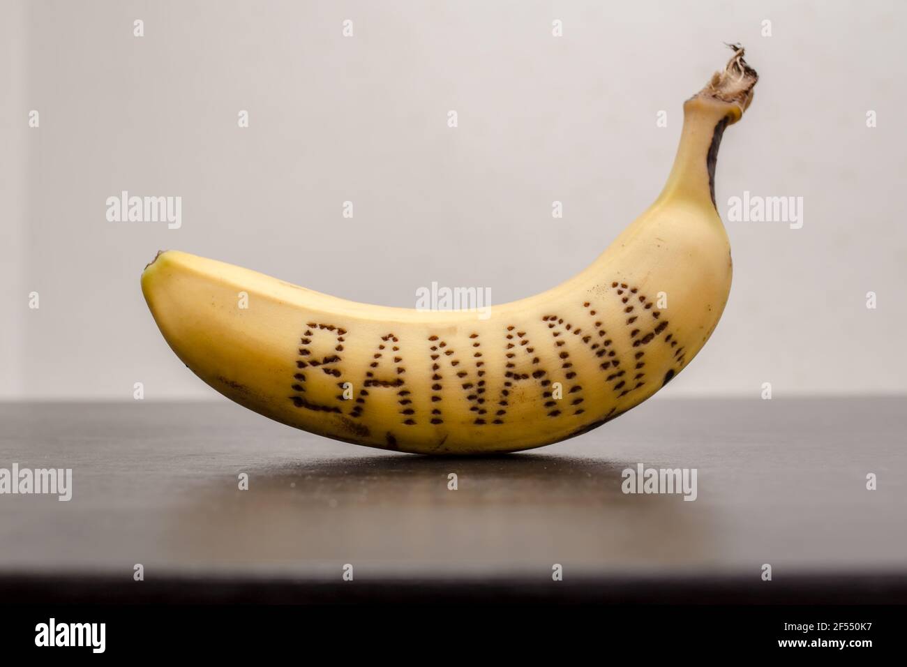 Banana with handwritten inscription on the peel, on a black table, on a ...
