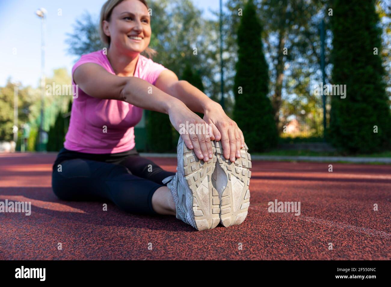 a woman stretches her legs in the stadium Stock Photo - Alamy