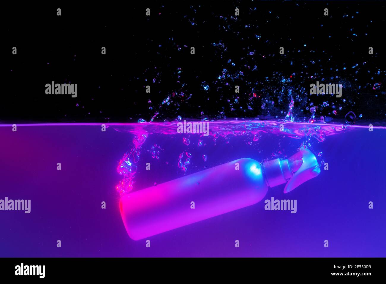 Skincare product bottle falling into water against black background in ...
