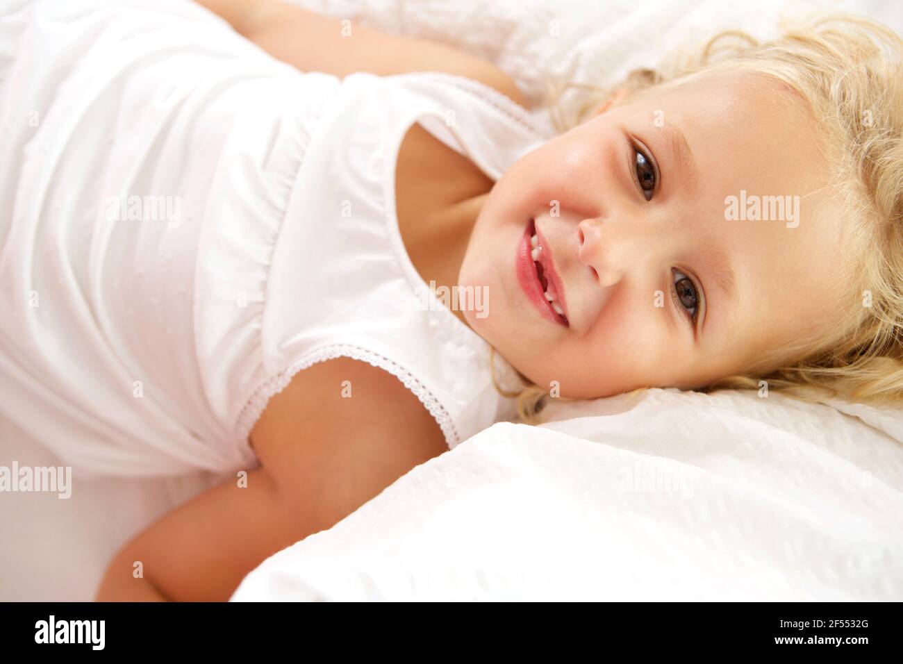 Close up portrait of beautiful little girl lying on bed Stock Photo - Alamy