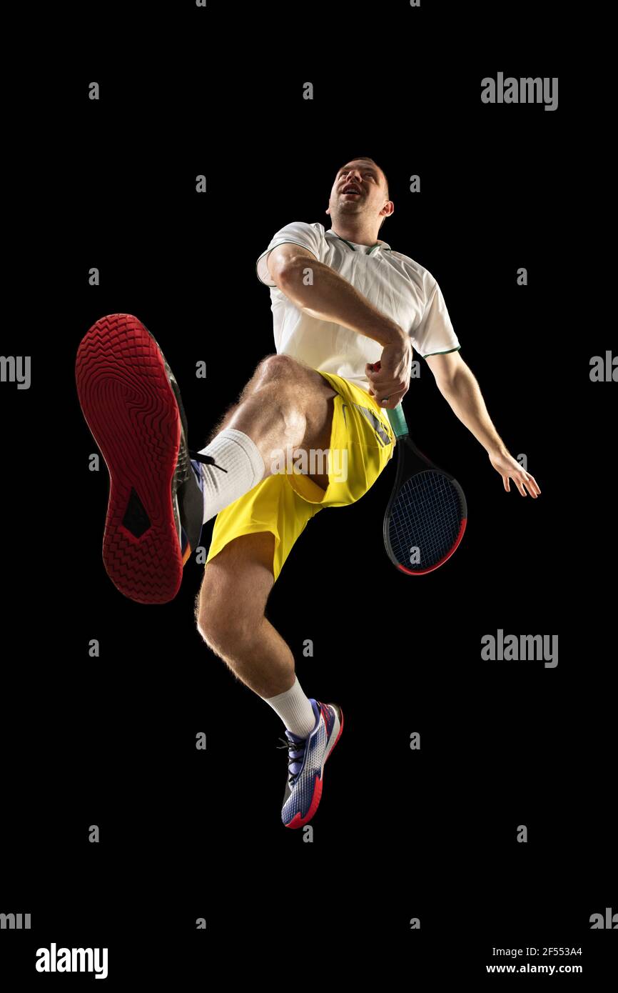 Young caucasian tennis player in action, motion isolated on black ...