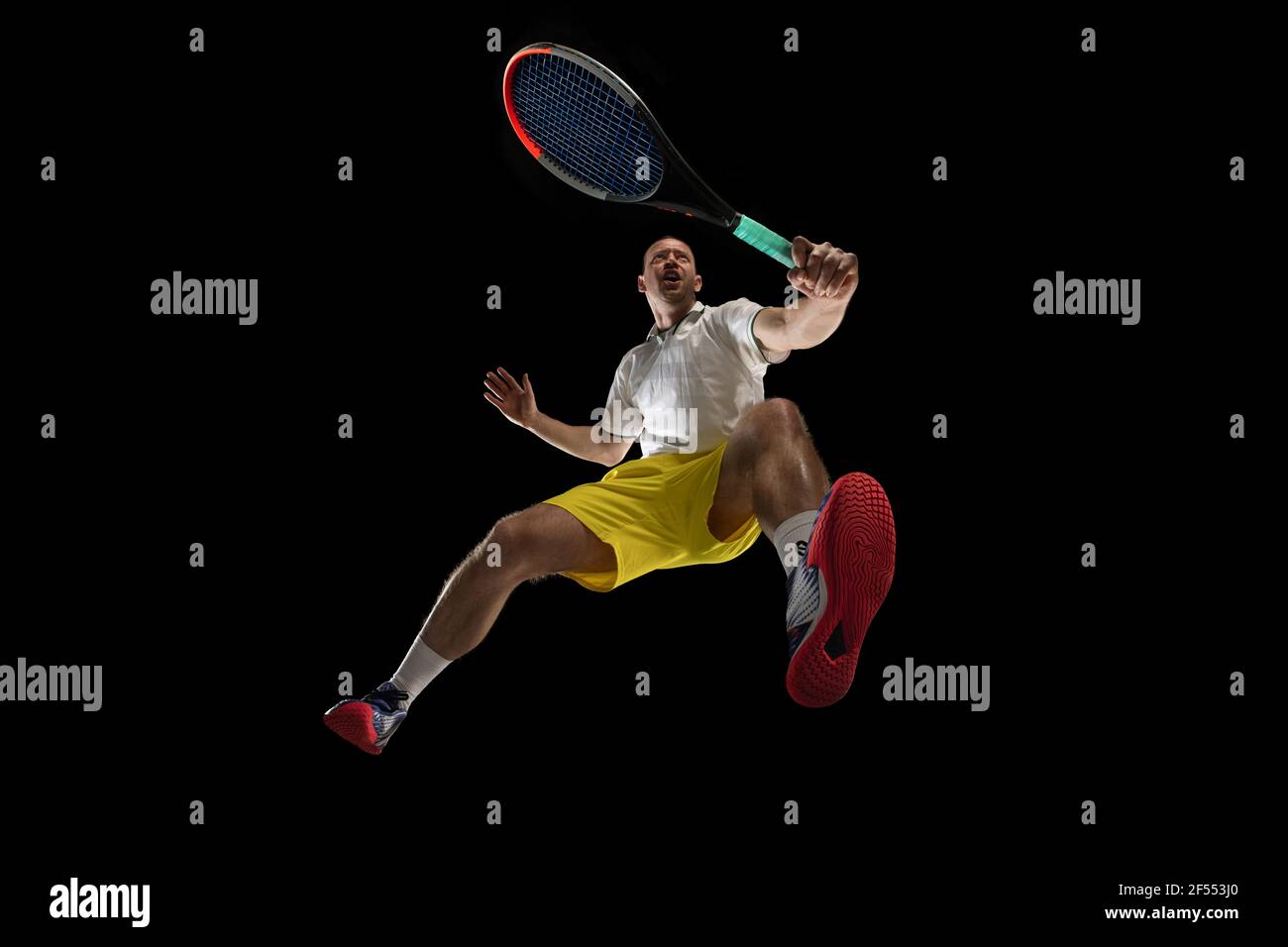 Young caucasian tennis player in action, motion isolated on black ...
