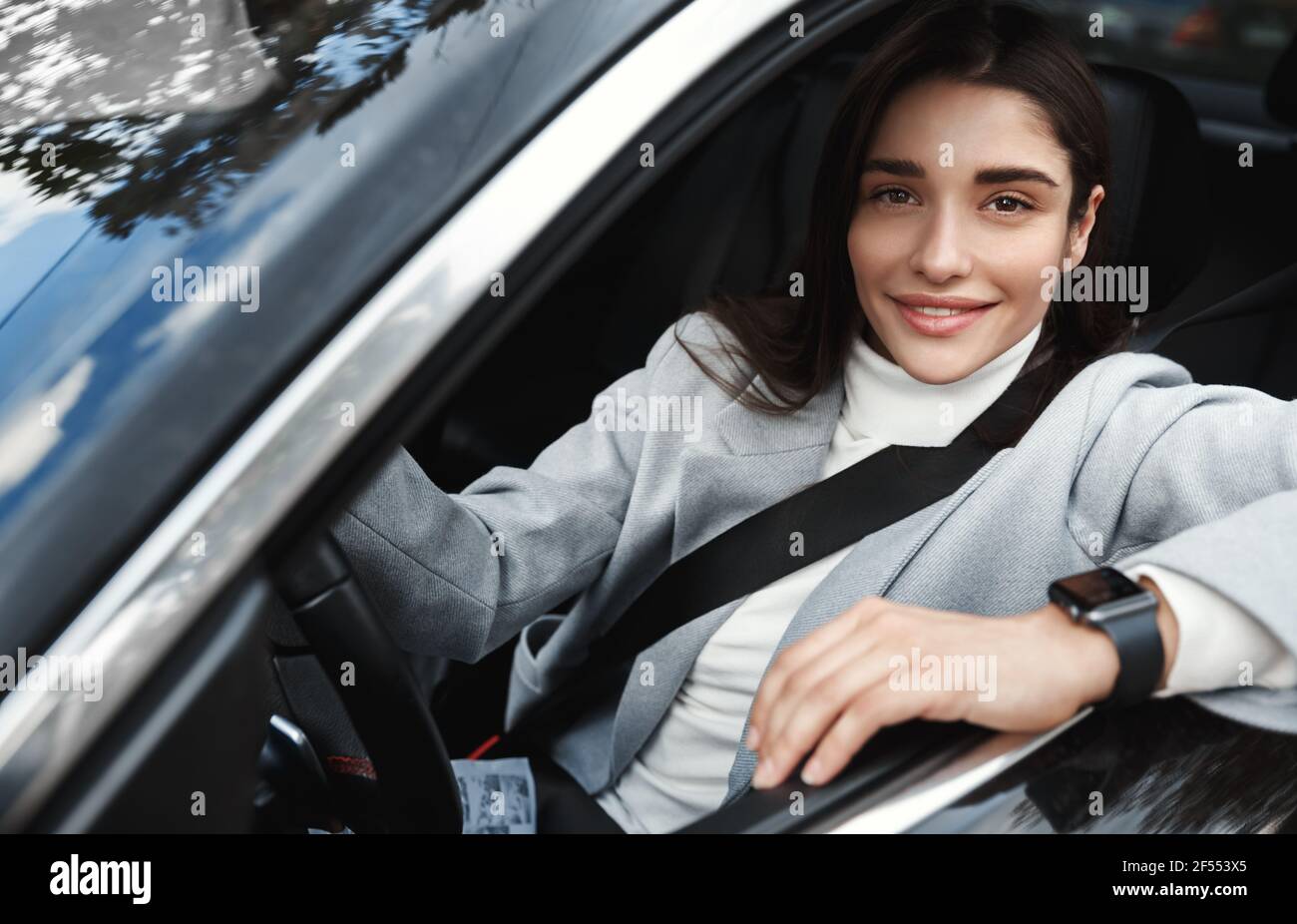 Successful businesswoman driving her car to work, wearing seatbelt and ...