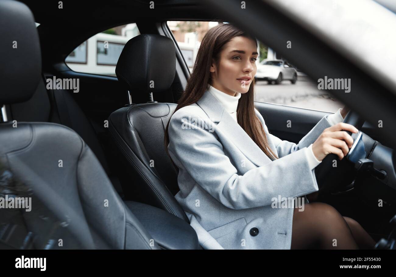 Elegant woman driving her car, looking at rear window. Businesswoman ...