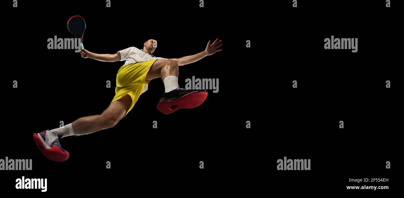 Young caucasian tennis player in action, motion isolated on black ...