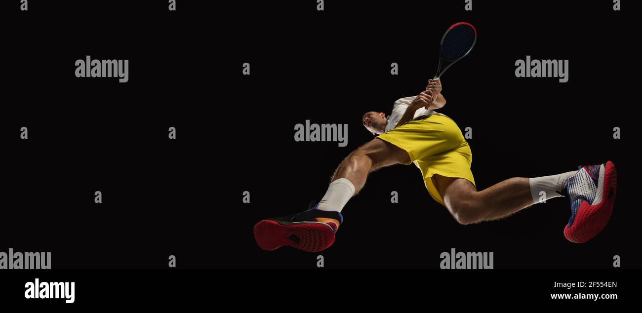 Young caucasian tennis player in action, motion isolated on black ...