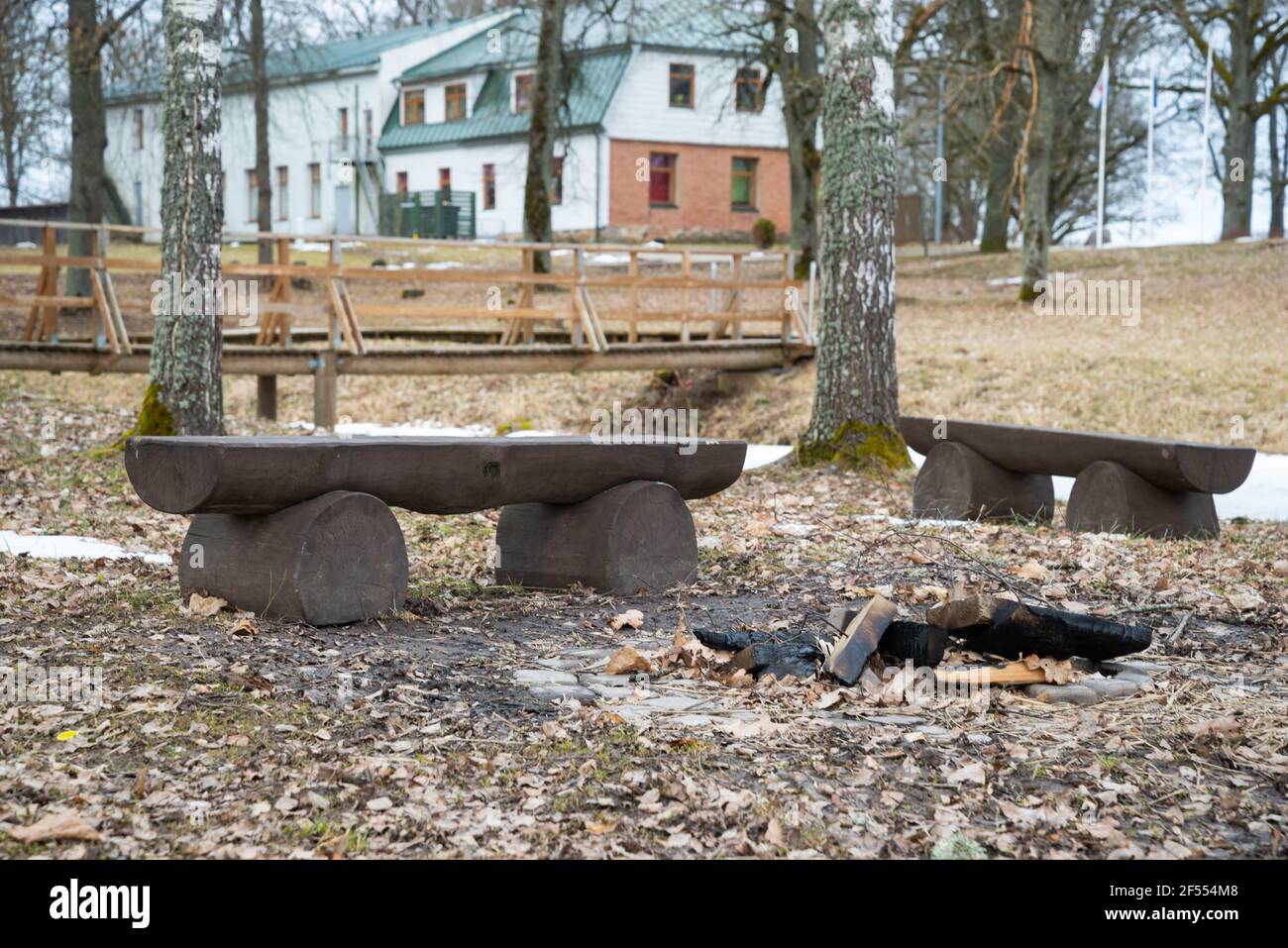 wooden bench made of logs and a fireplace in nature. Rest place in the ...