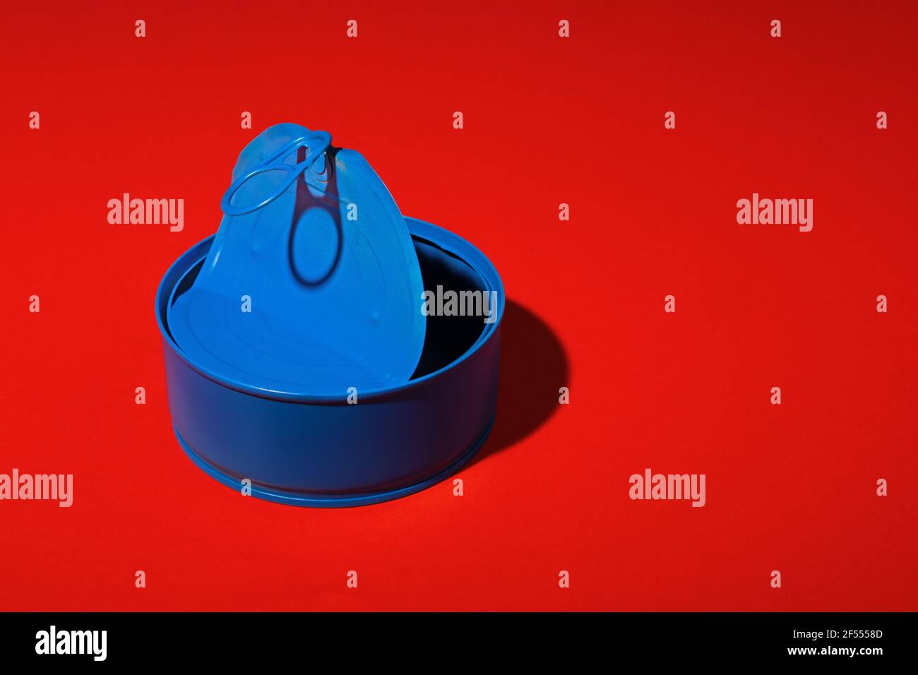 Blue tin can on dark red background Stock Photo - Alamy