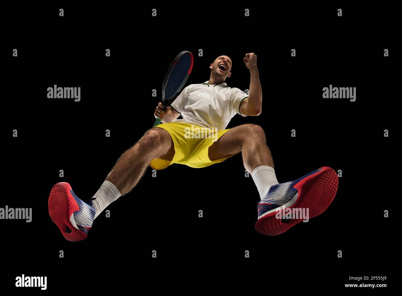 Young caucasian tennis player in action, motion isolated on black ...