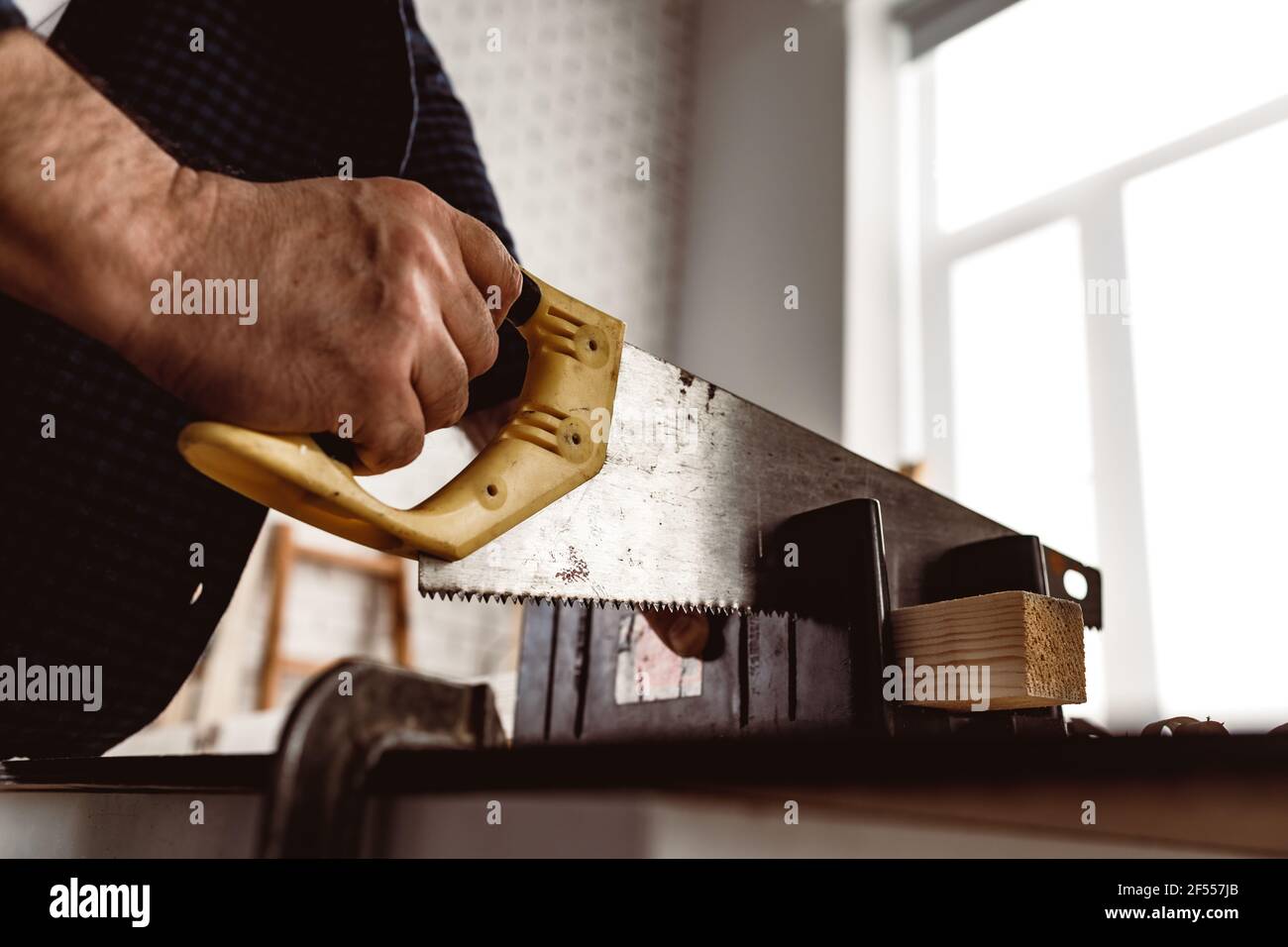 Carpenter saws a wooden block in a workshop Stock Photo - Alamy
