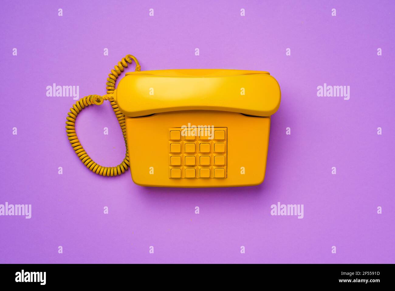 Yellow landline telephone on purple background close up Stock Photo - Alamy