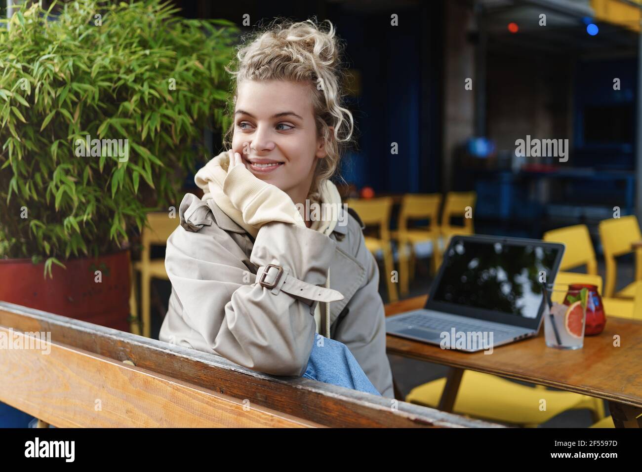 Rear view pretty smiling girl sitting outdoor cafe and watching ...