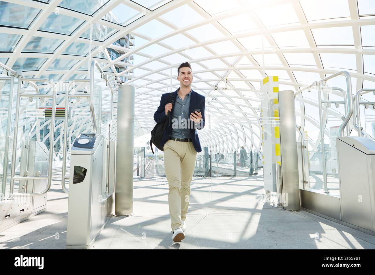 Full body portrait of happy man walking by automated turnstile with ...