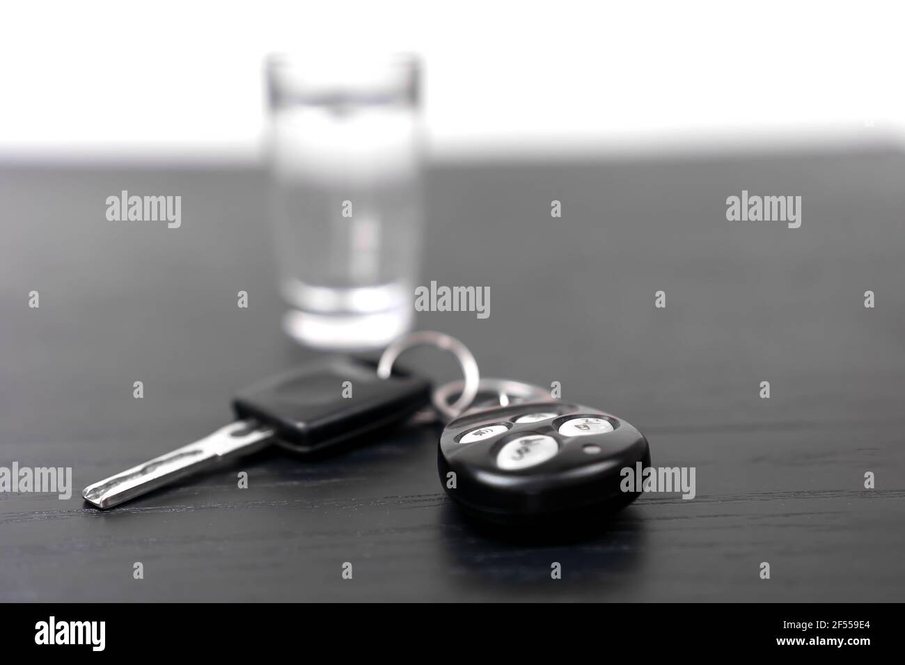 On the black table are the car keys and a shot of vodka close-up with ...