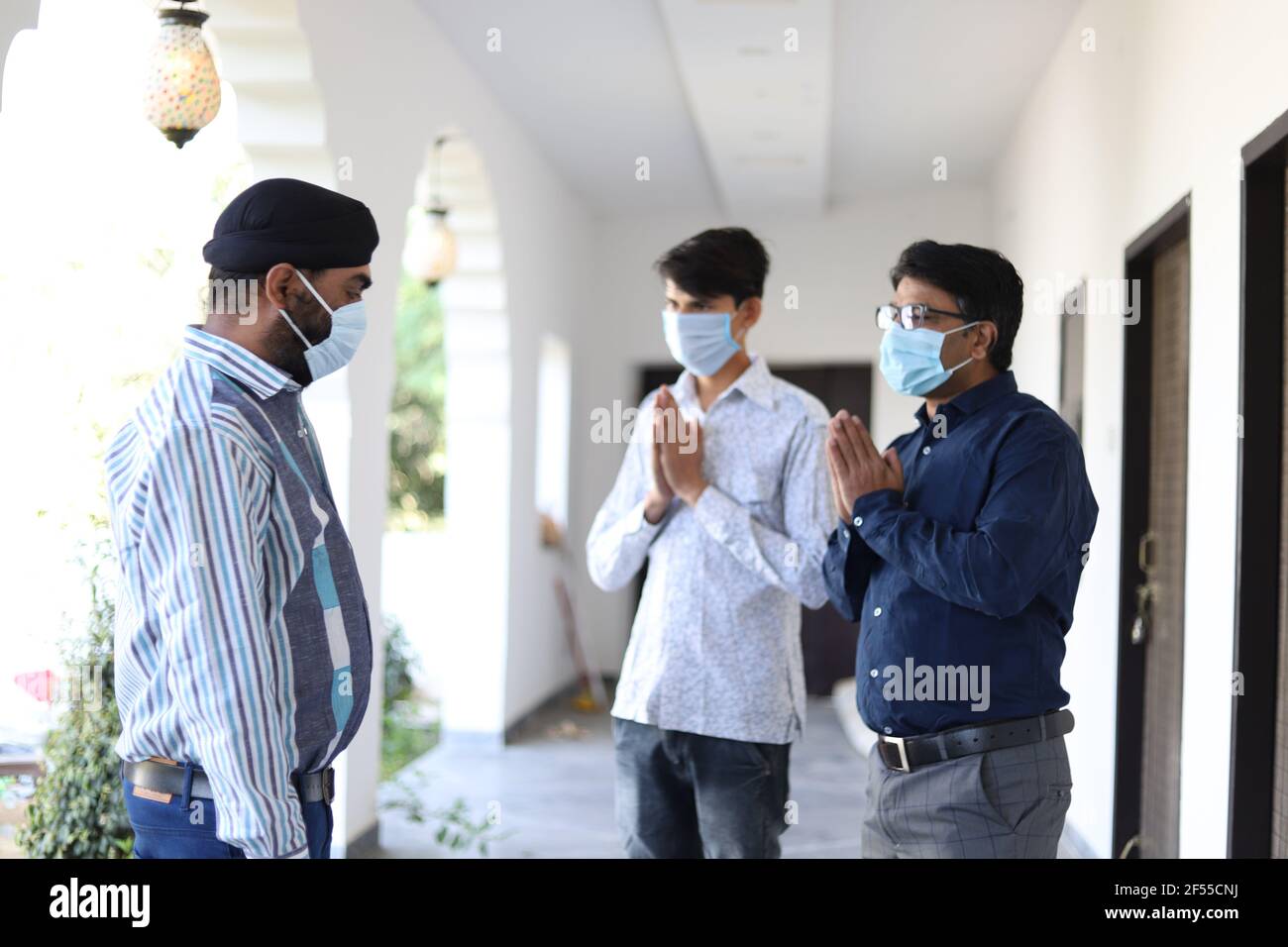 Closeup shot of two Indian men with masks showing thanks to the other ...