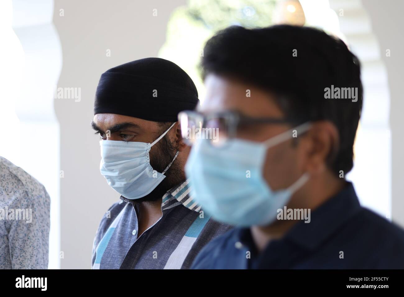Selective shot of two Indian men with the mask on the white wall ...