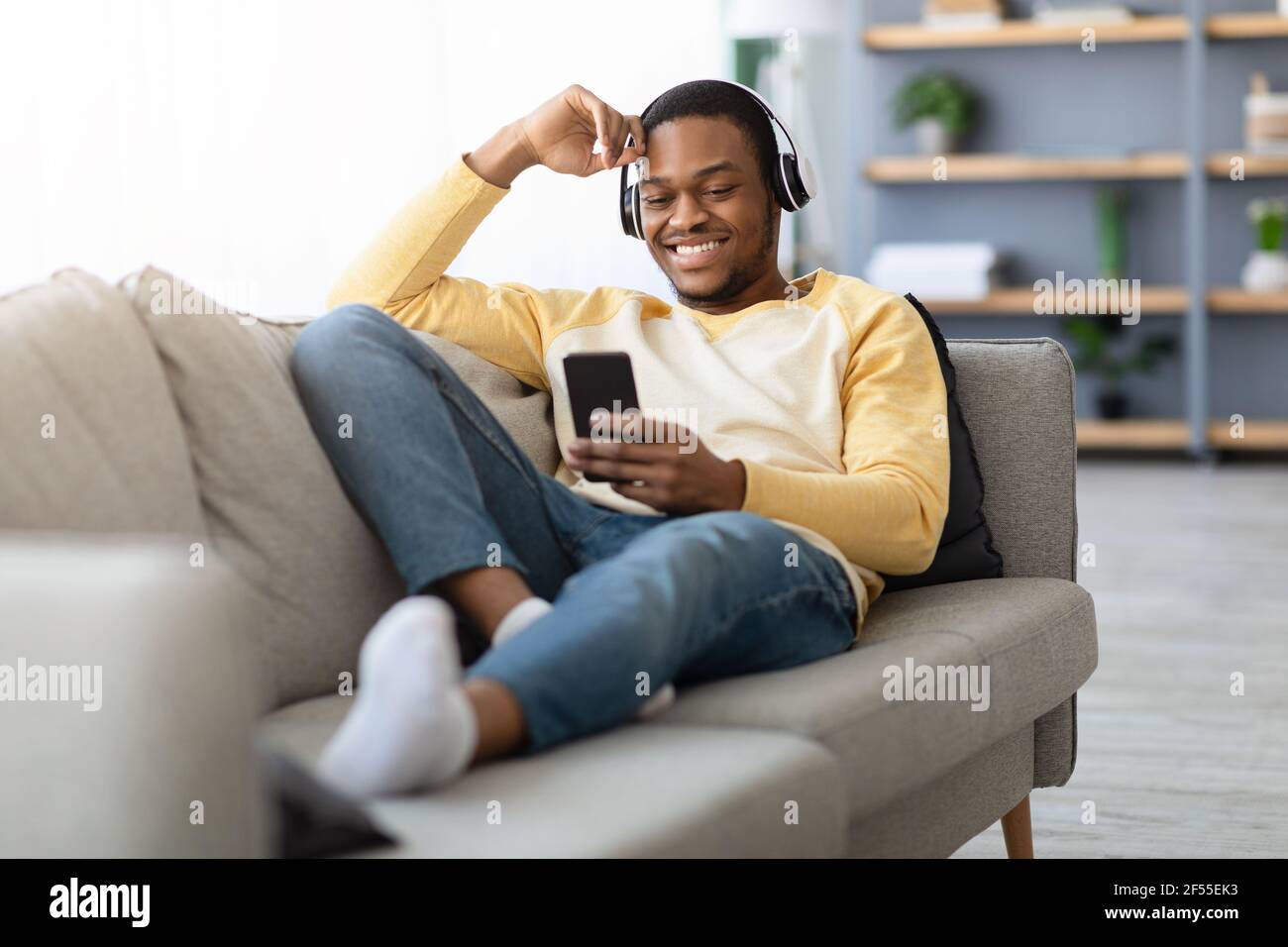 Happy black guy watching videos on mobile phone Stock Photo - Alamy