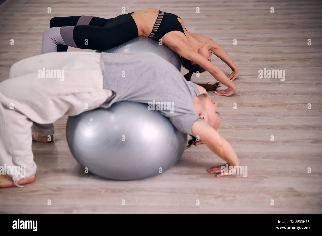 Competent trainer demonstrating exercise for straight back Stock Photo ...