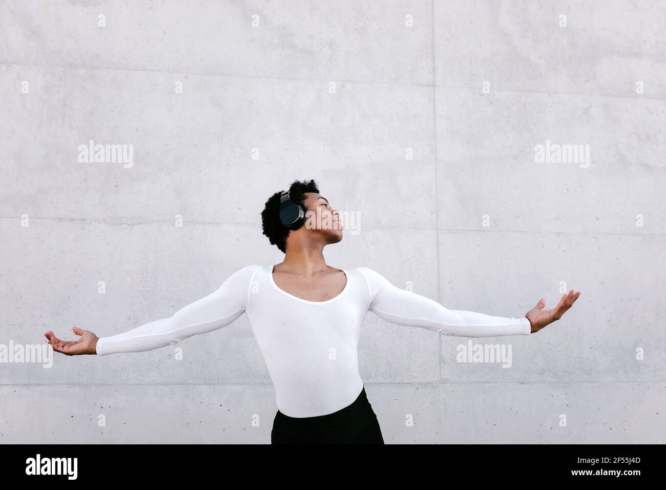 Young male dancer with arms outstretched doing rehearsal against white ...