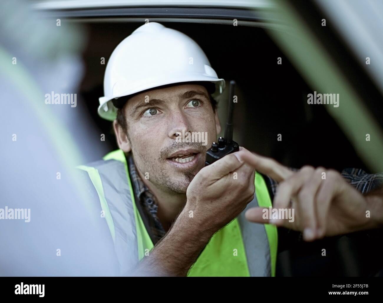 Portrait of construction worker sitting in car and talking on walkie ...