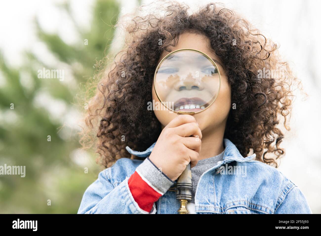 Cute boy holding magnifying glass in front of face Stock Photo - Alamy