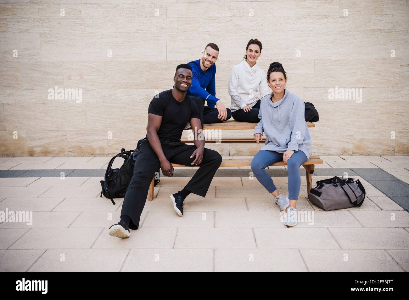 Smiling sports people sitting together on bench Stock Photo - Alamy