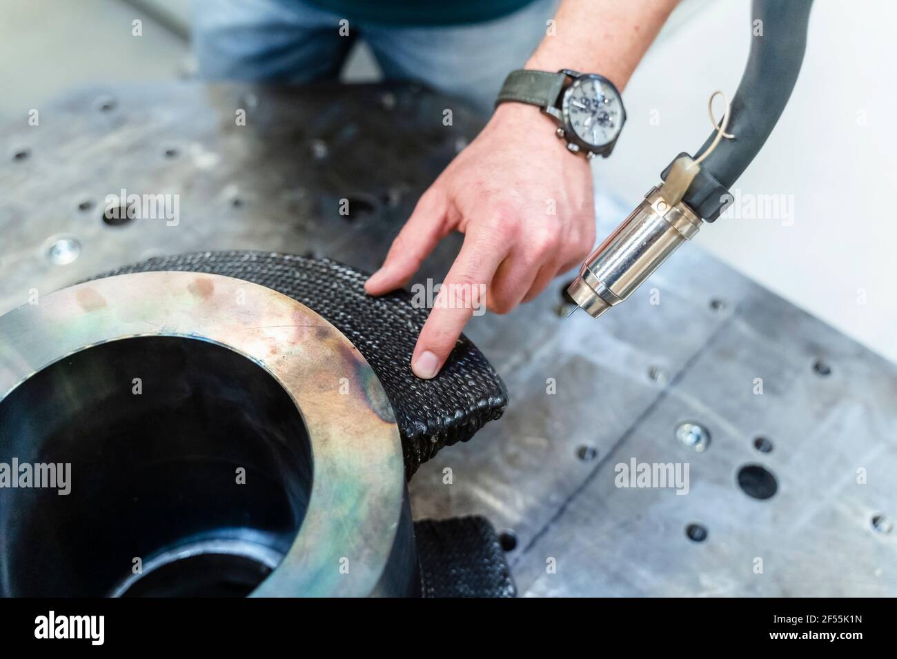 Male engineer using automatic welding torch on equipment in factory ...