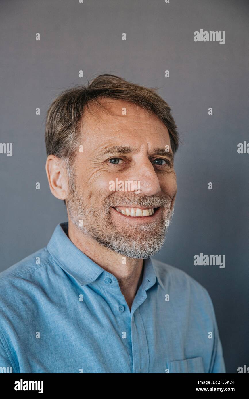 Smiling man with gray eyes on gray background Stock Photo - Alamy