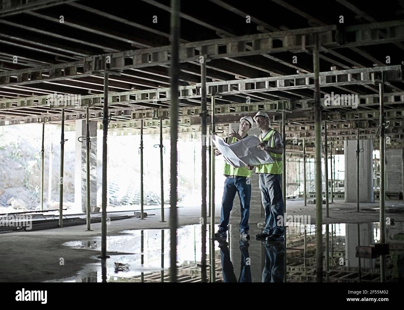 Two male construction workers talking over plans at construction site ...