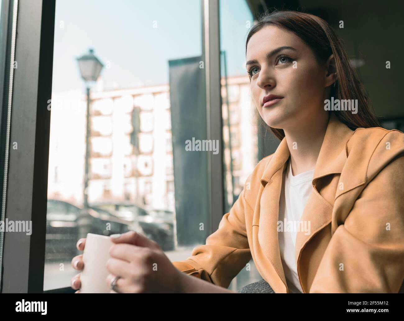 Beautiful woman sitting by glass window at coffee shop Stock Photo - Alamy