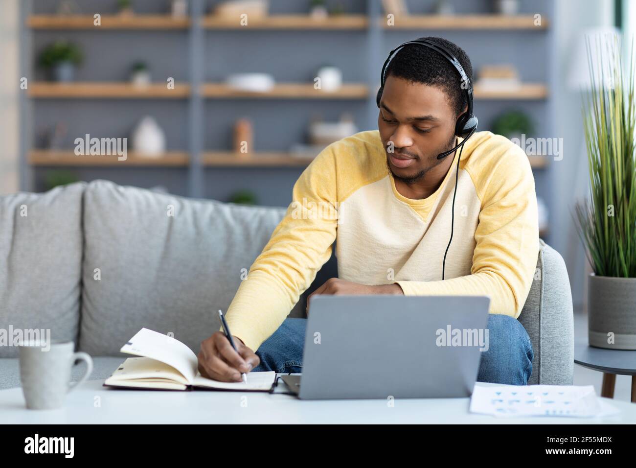 Black guy attending online training from home, taking notes Stock Photo ...